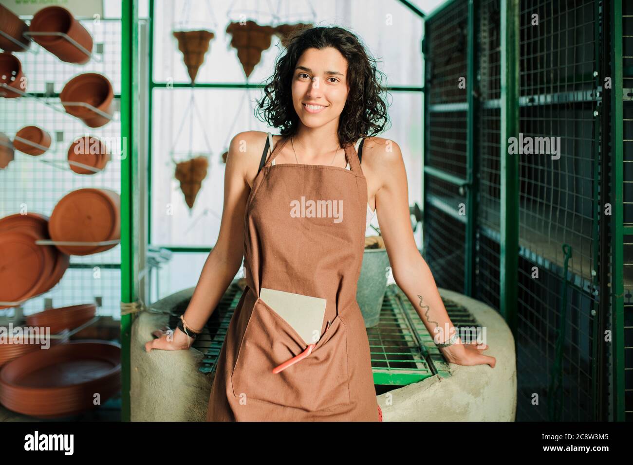 Young shop assistant in her ceramic shop surrounded by her products ...