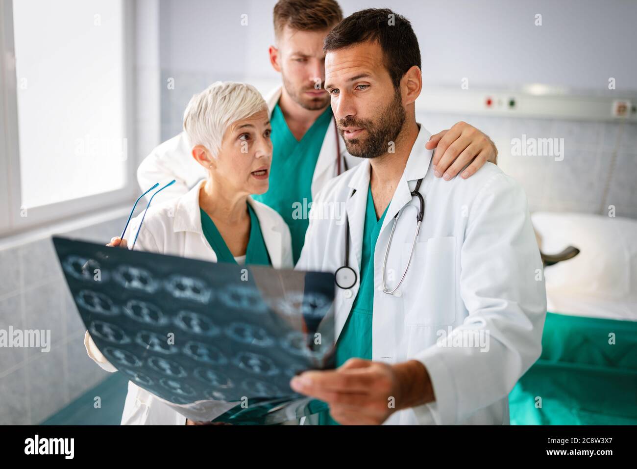 Doctors discussing patient's diagnosis looking at x-rays in a hospital ...
