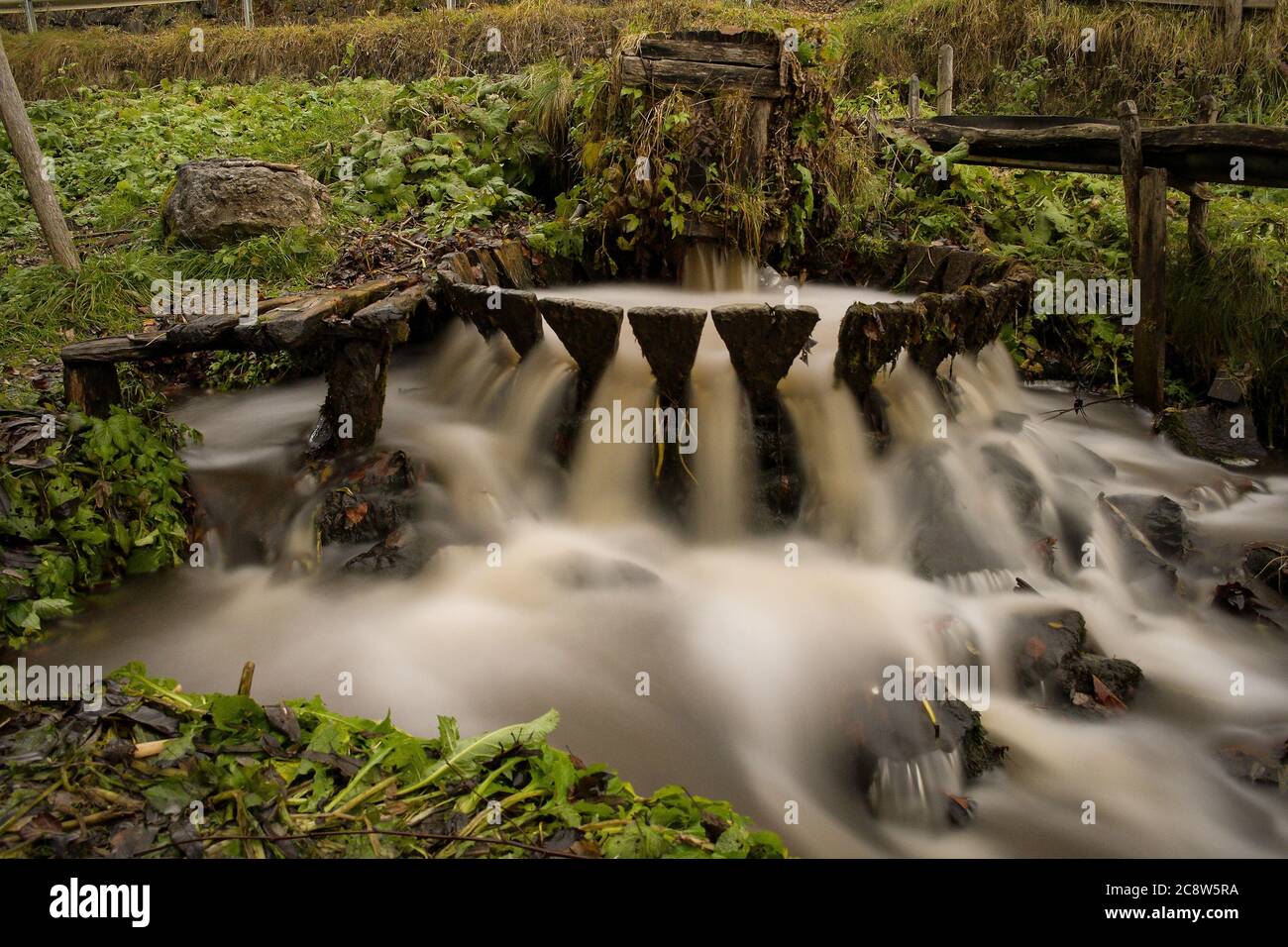 Traditional natural wash machine (valtoare) under a stream of water in ...