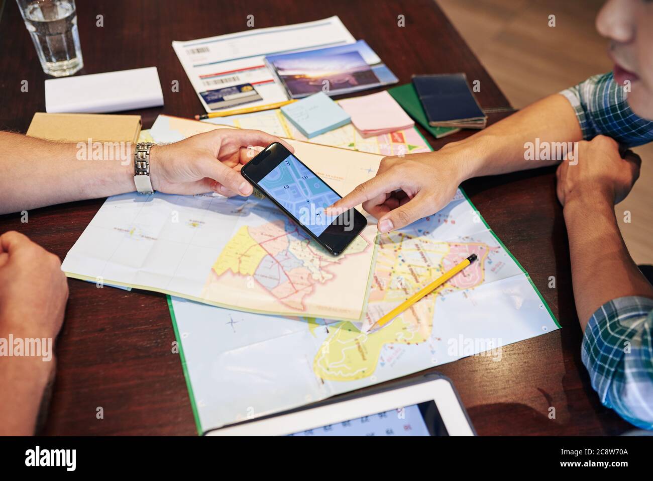 Young people planning trip, they are checking paper maps and online ...