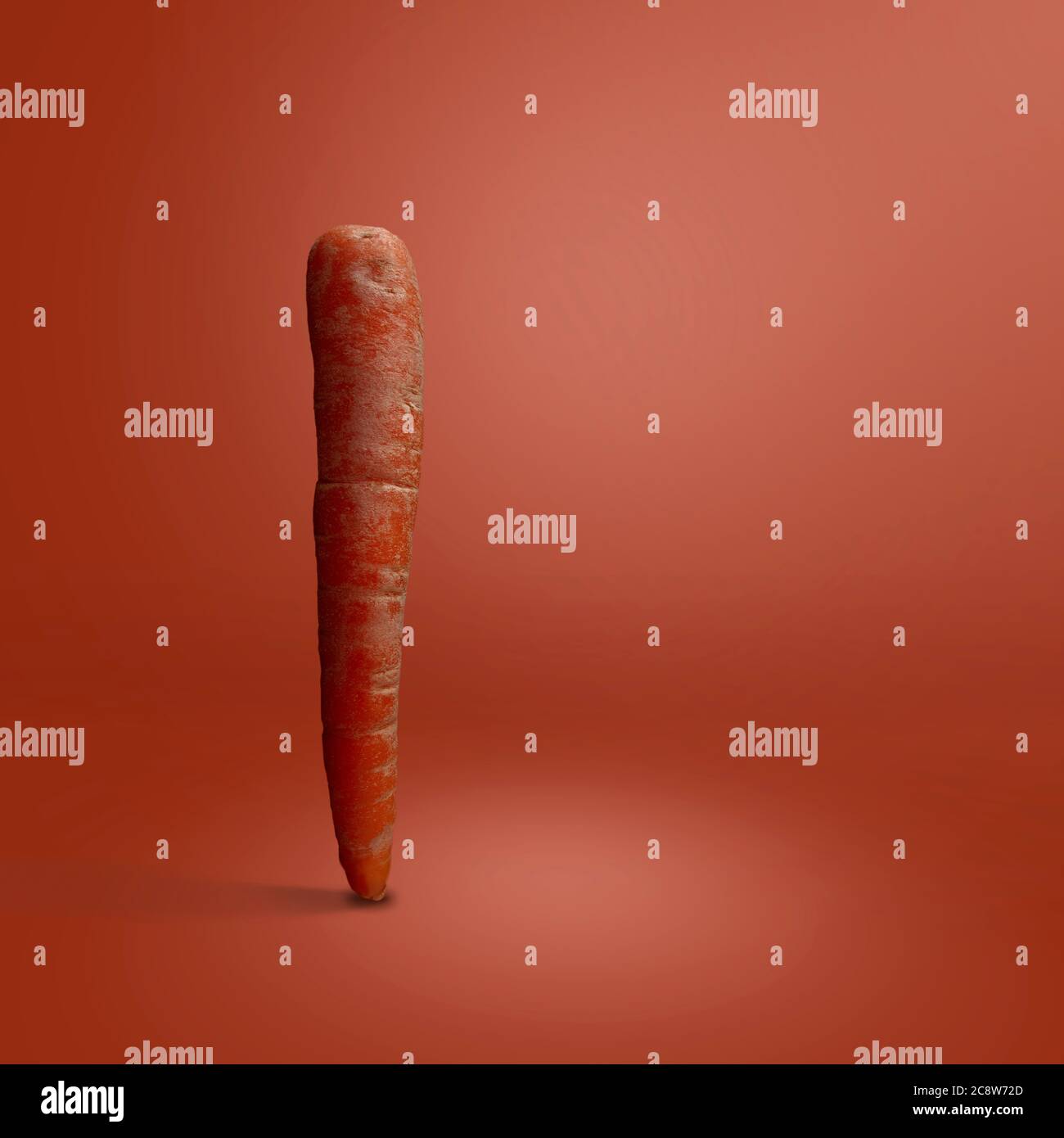 A single carrot stood upright against an orange background Stock Photo ...