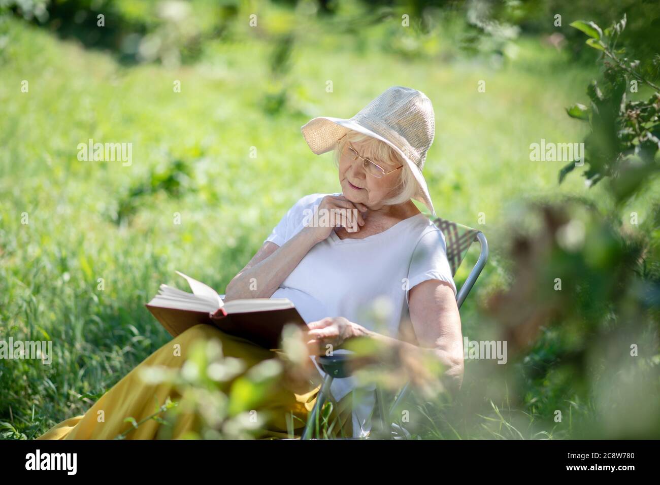 Relaxed elderly woman reading a book outdoor Stock Photo - Alamy