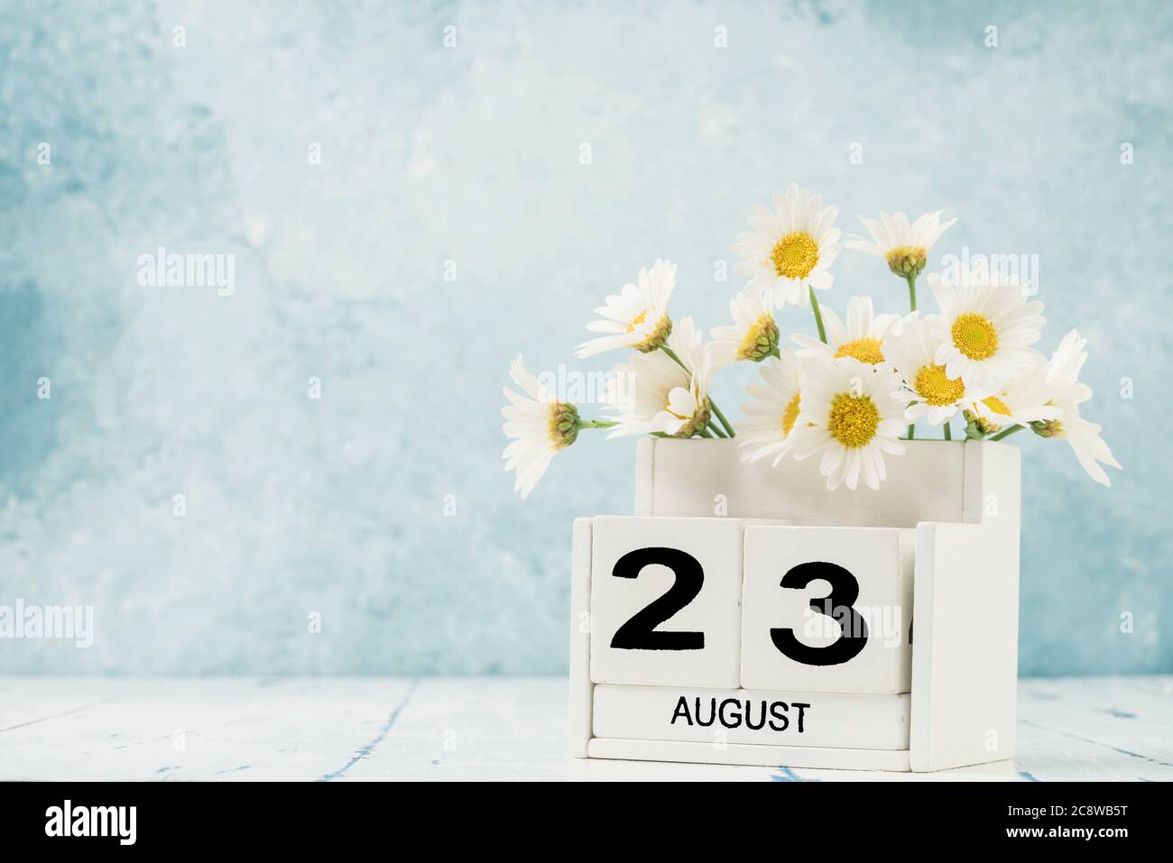 White cube calendar for august decorated with daisy flowers over blue ...