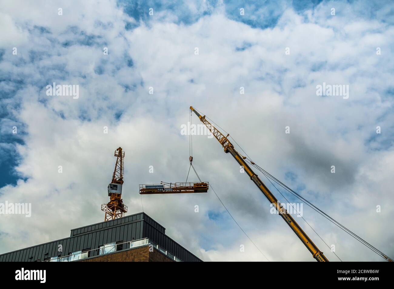 Mobile crane taking down tower crane during apartment construction in ...