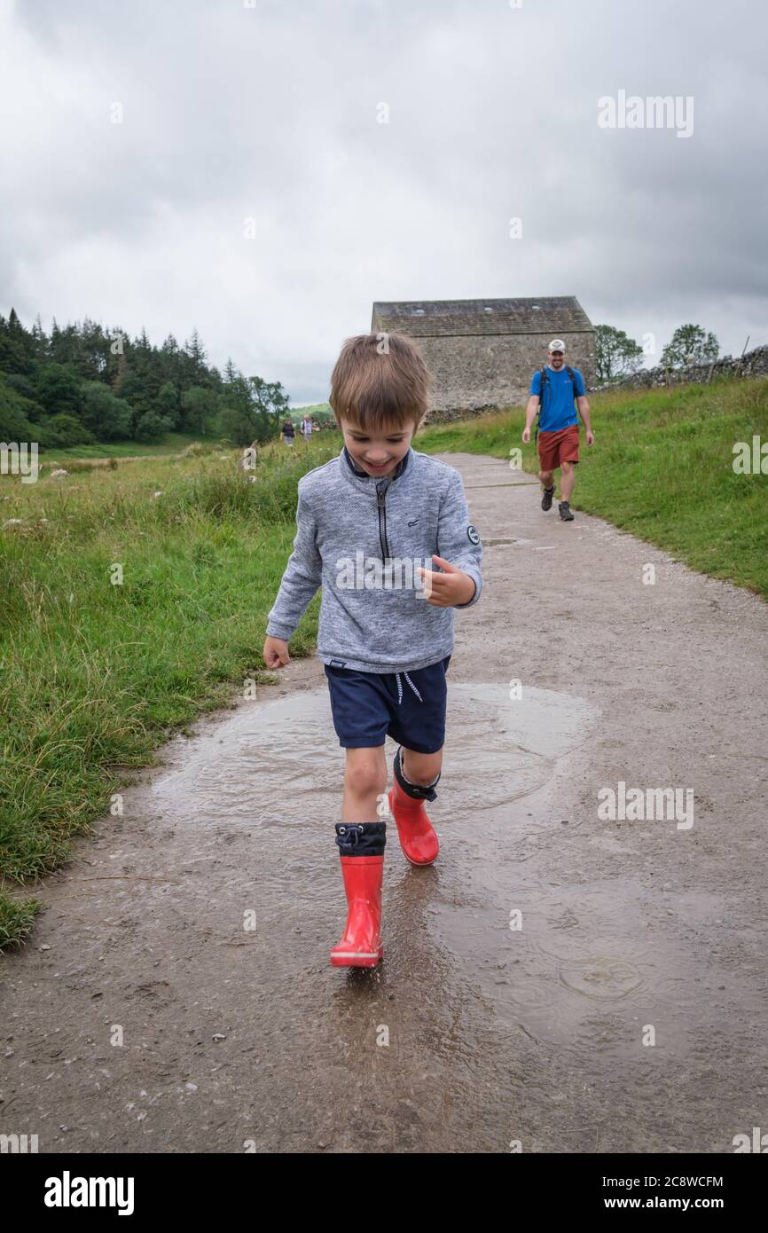 Four Year Old boy splashing in a puddle on a path at Gordale in the ...