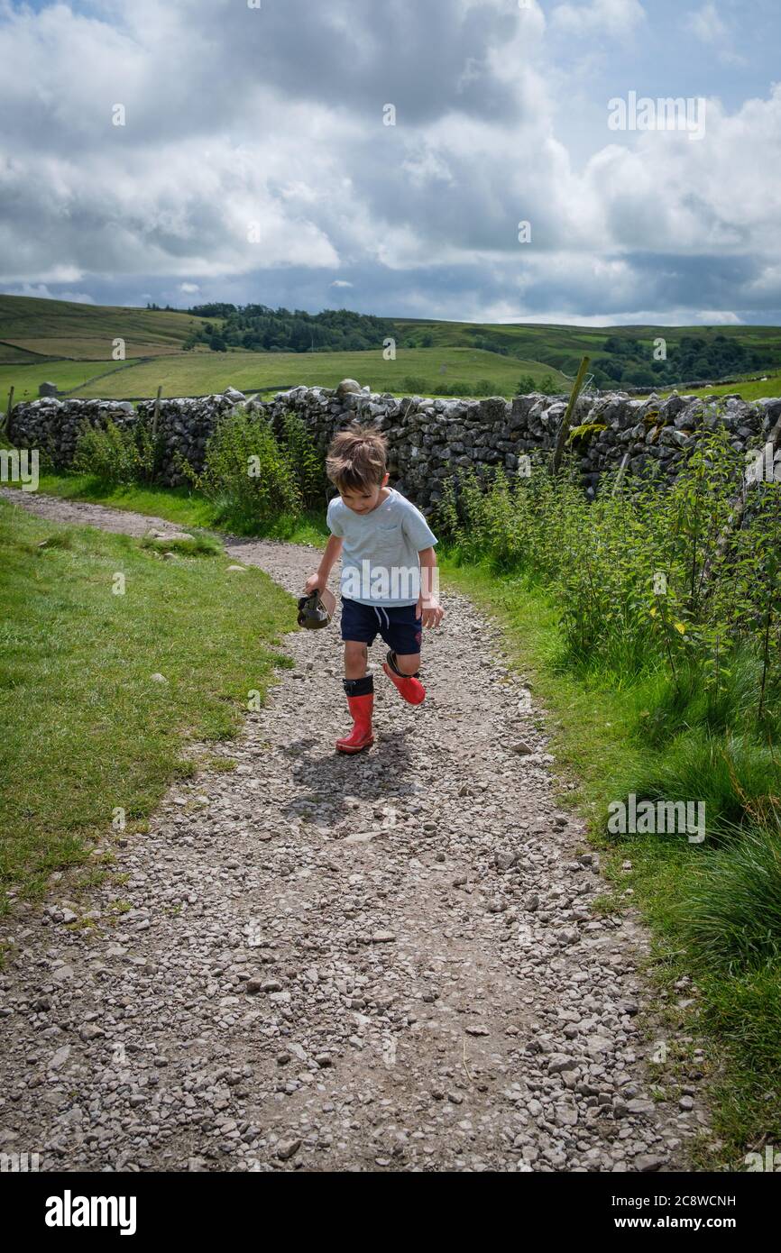Four Year Old boy running up a path at Gordale in the Yorkshire Dales ...