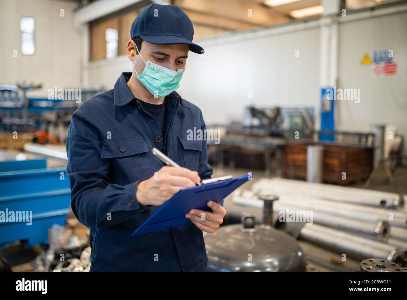 Industrial worker writing on a document in a factory Stock Photo - Alamy