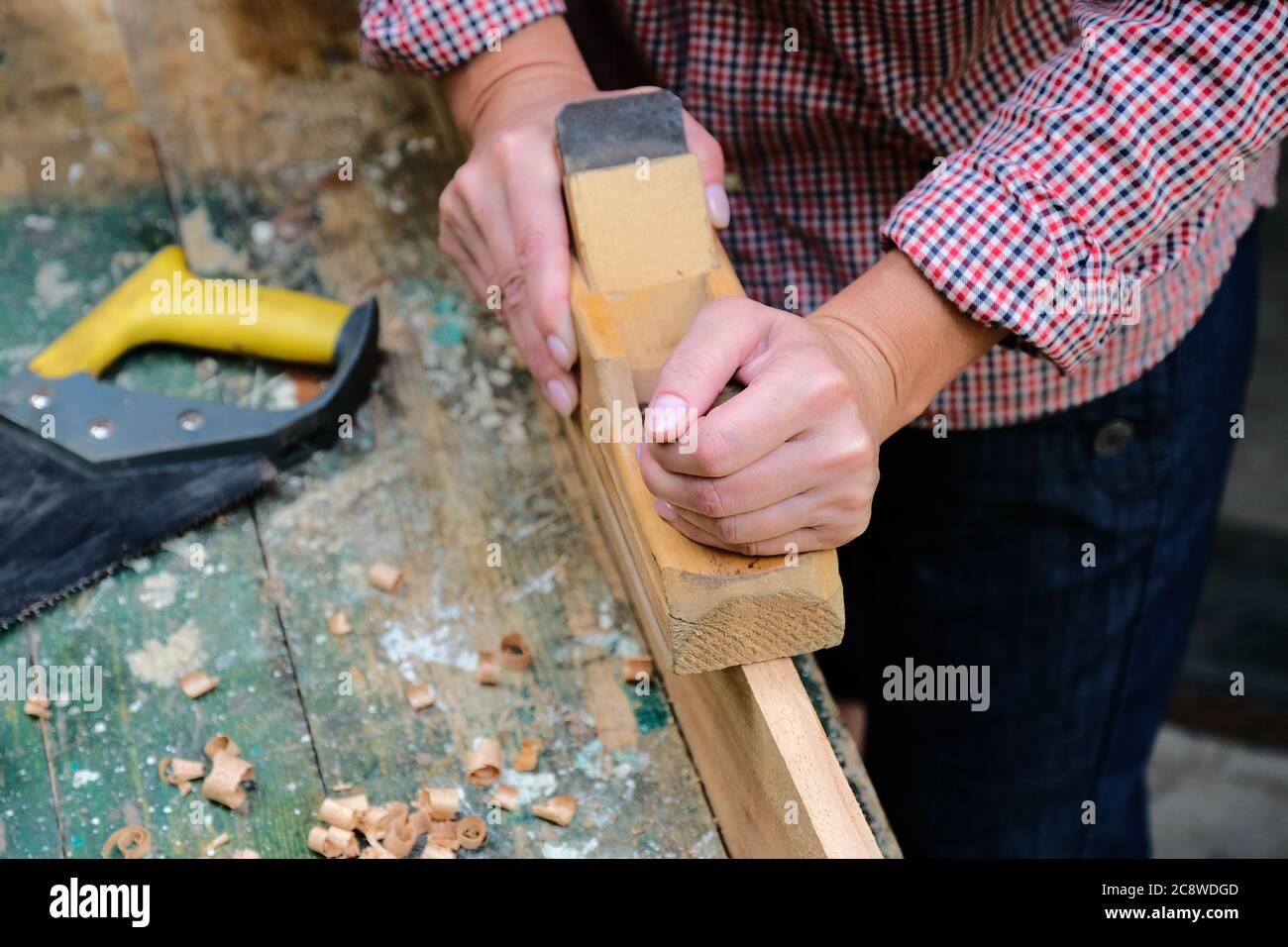 Female carpenter works with wood planer in workshop. Top view workbench ...