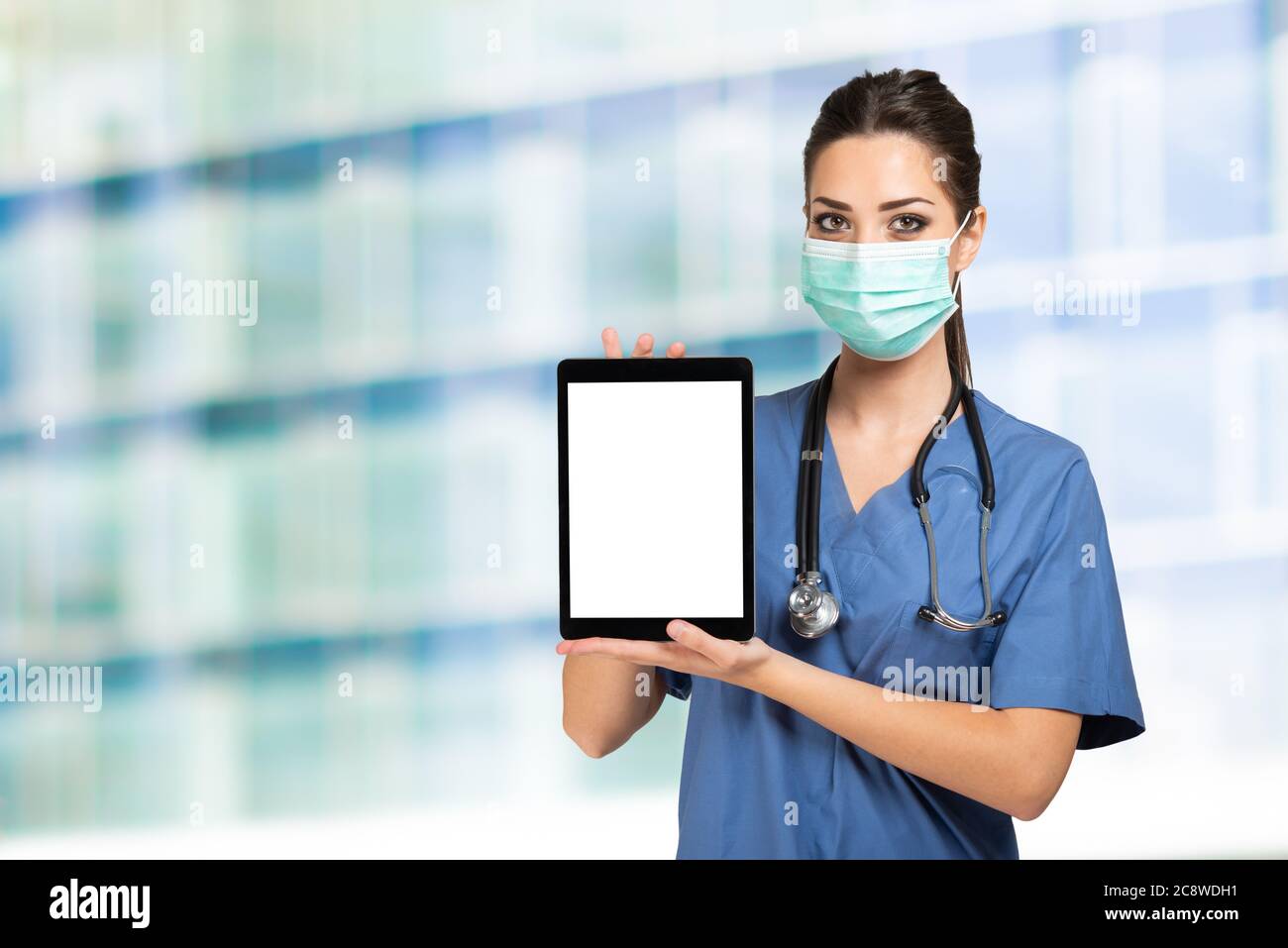 Masked nurse doctor showing a tablet with a white screen Stock Photo ...