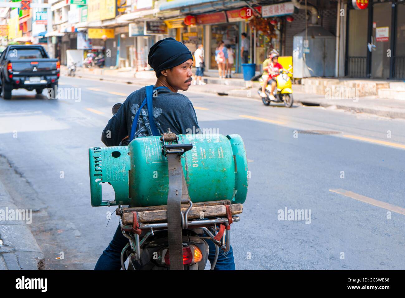 A man carries a gas cylinder on a motobike. Delivery of gas cylinders ...