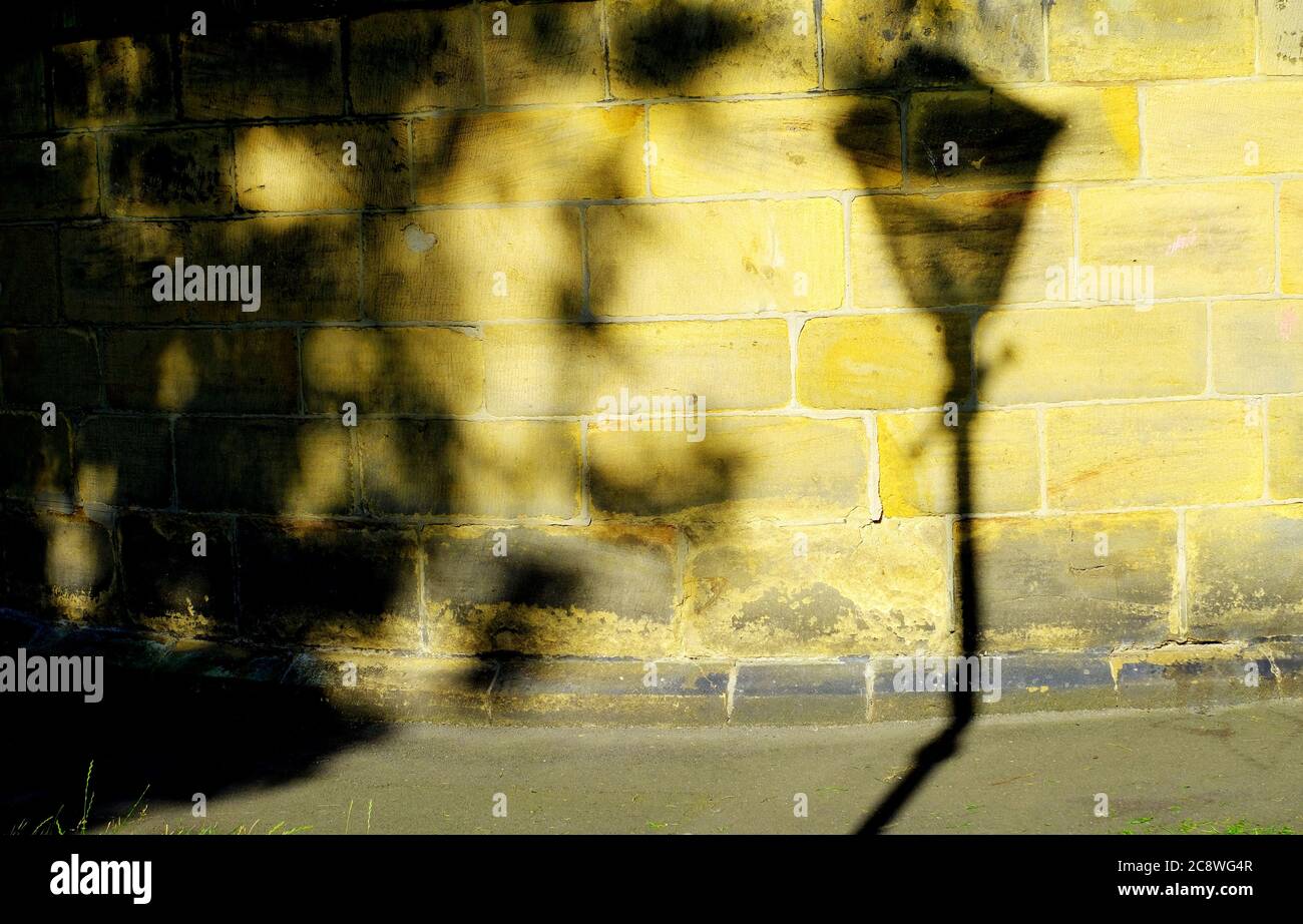 Old lamp post shadow against ancient stone church wall Stock Photo - Alamy