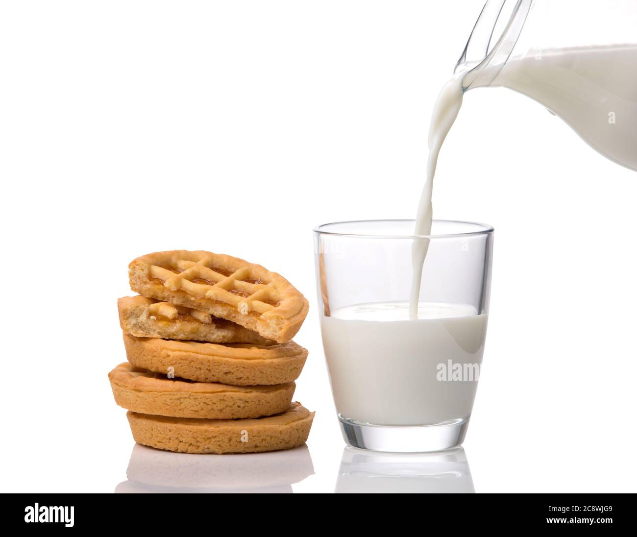 Pouring milk into the glass and cookies with jam isolated on white ...