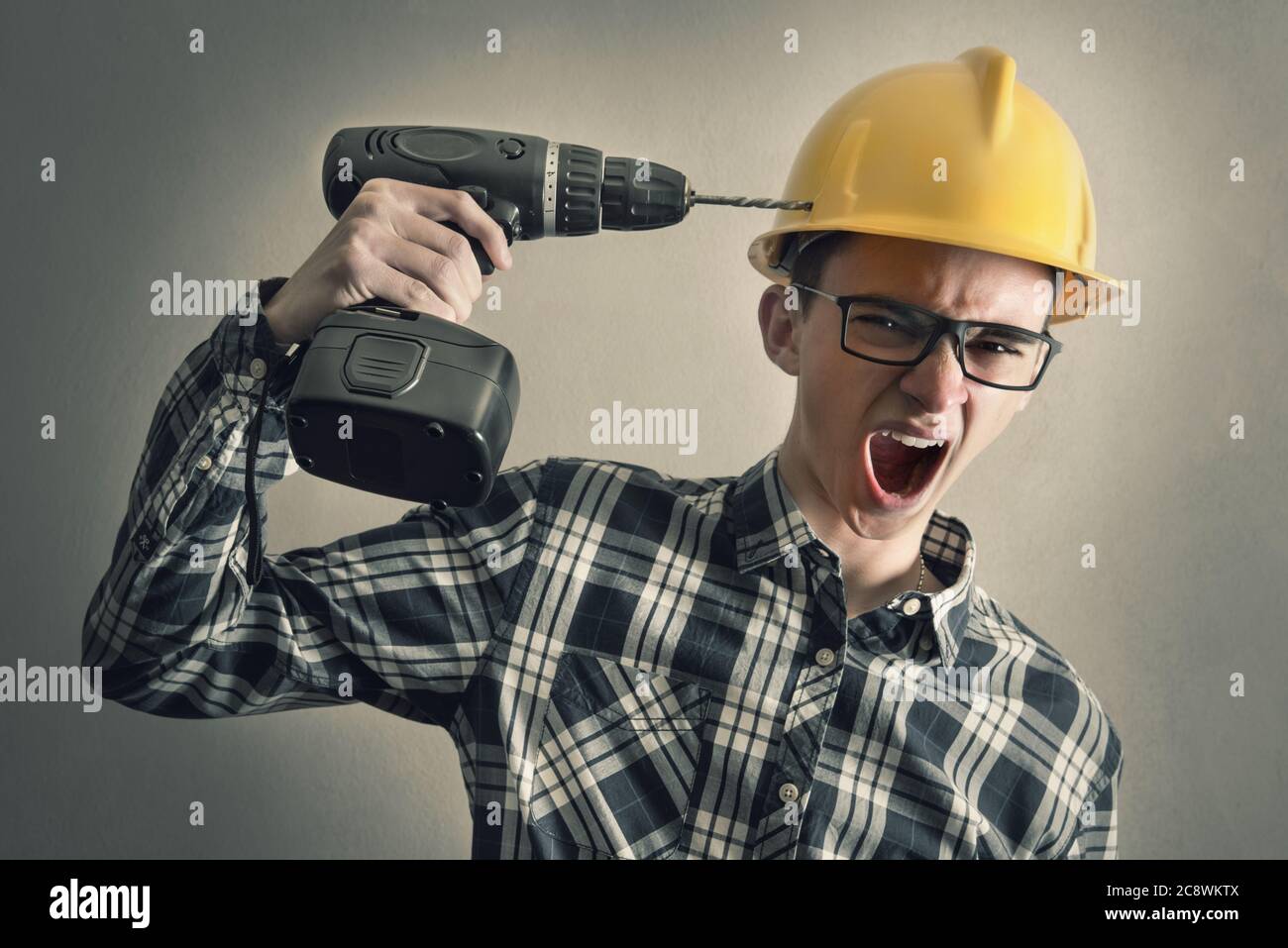 Young construction worker simulates shooting himself with a drill Stock ...