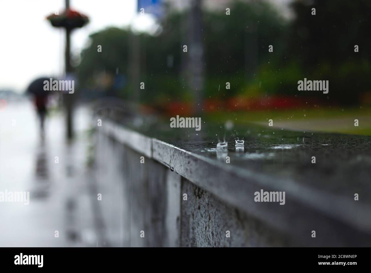 Urban landscape in the rain. Drops on the parapet along the sidewalk ...