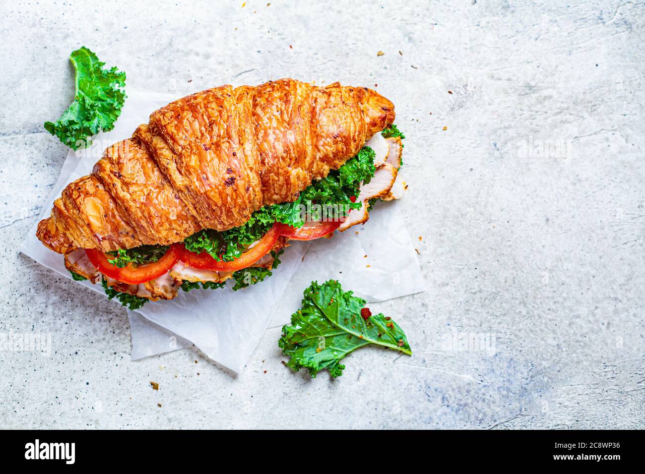 Homemade croissant sandwich with meat, vegetables and green kale, top ...