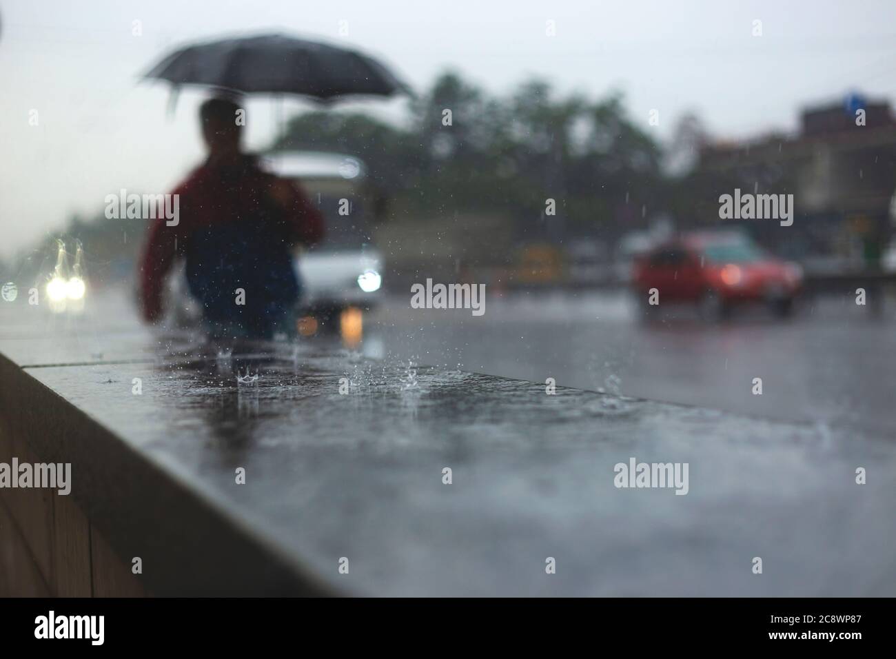 Urban rainy landscape. Drops on the parapet along sidewalk and road ...