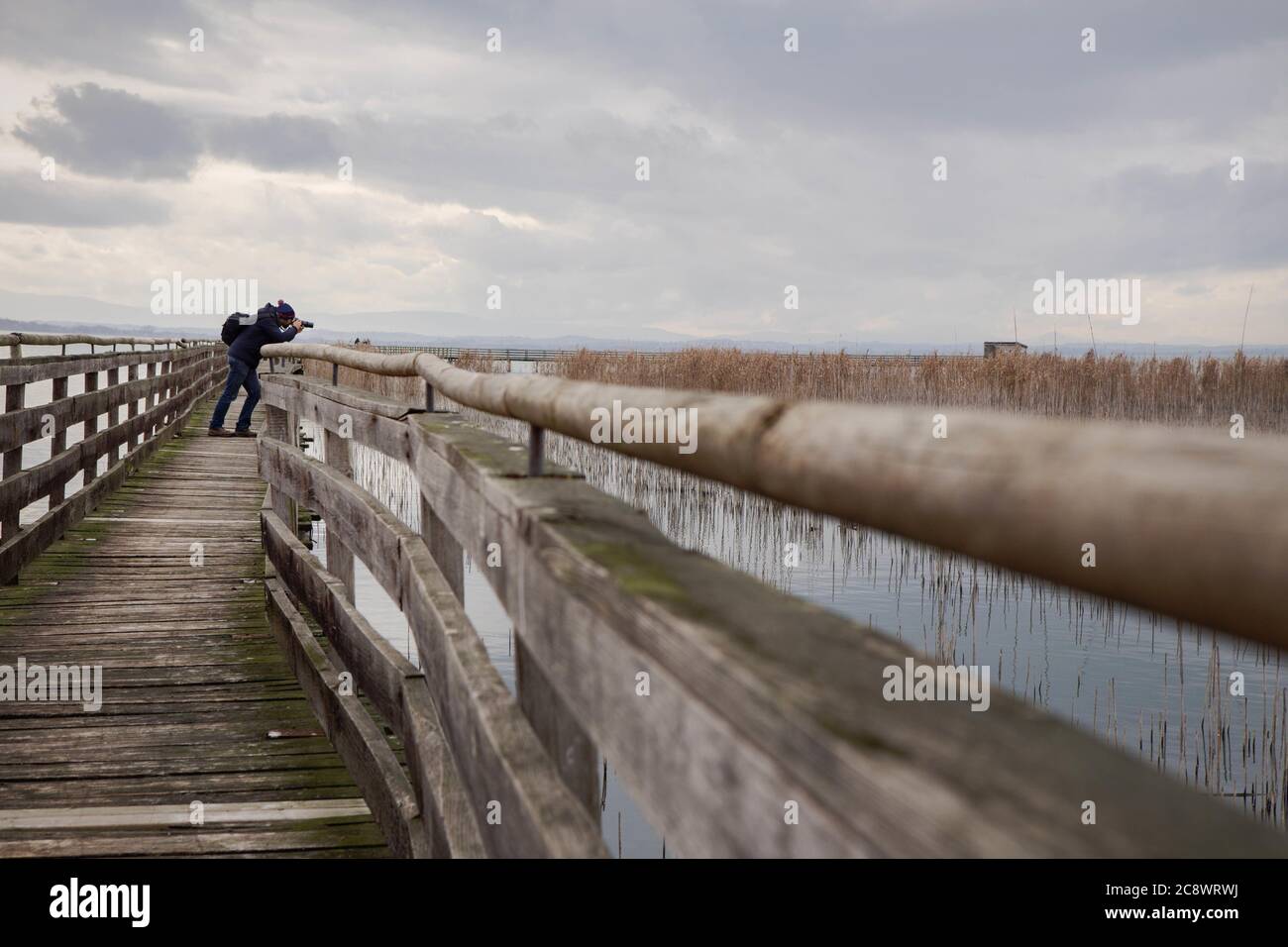 MAGIONE, ITALY - Jan 05, 2016: Man on a wooden bridge photographing the ...