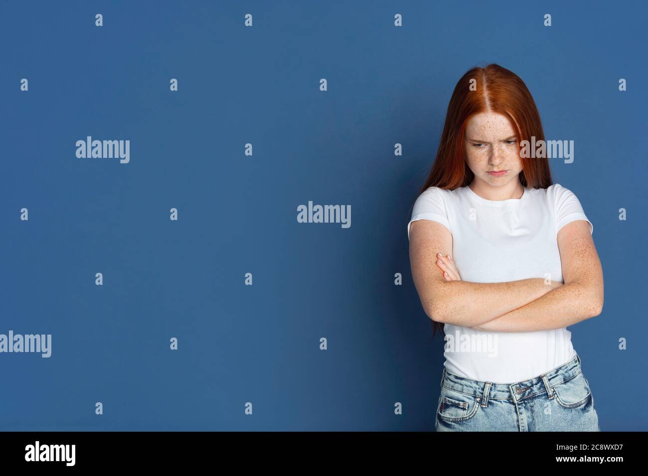 Sad, disappointed. Caucasian young girl's portrait on blue background ...