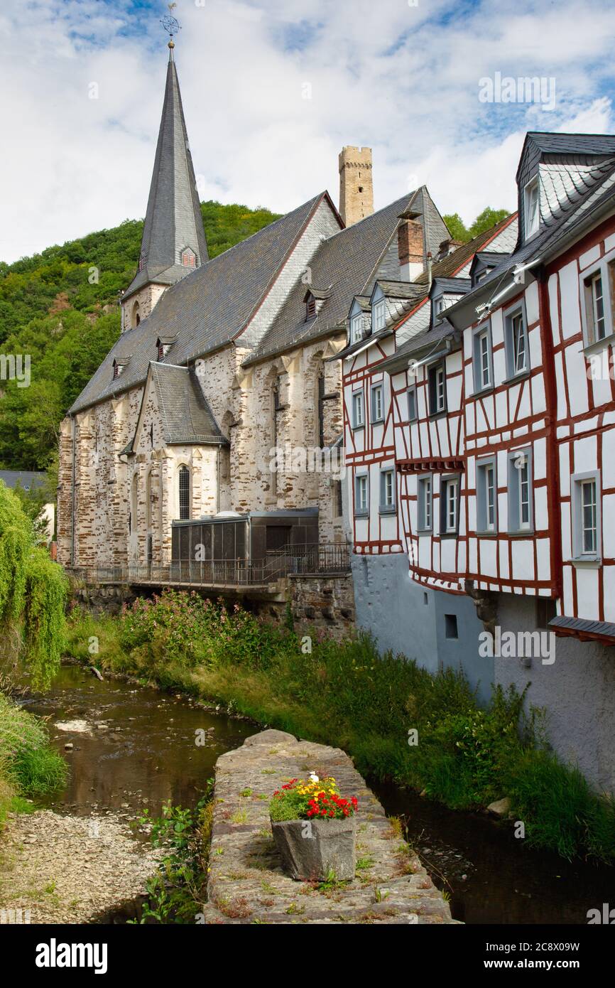 Rural scene with half-timbered houses and an old church beside a creek ...