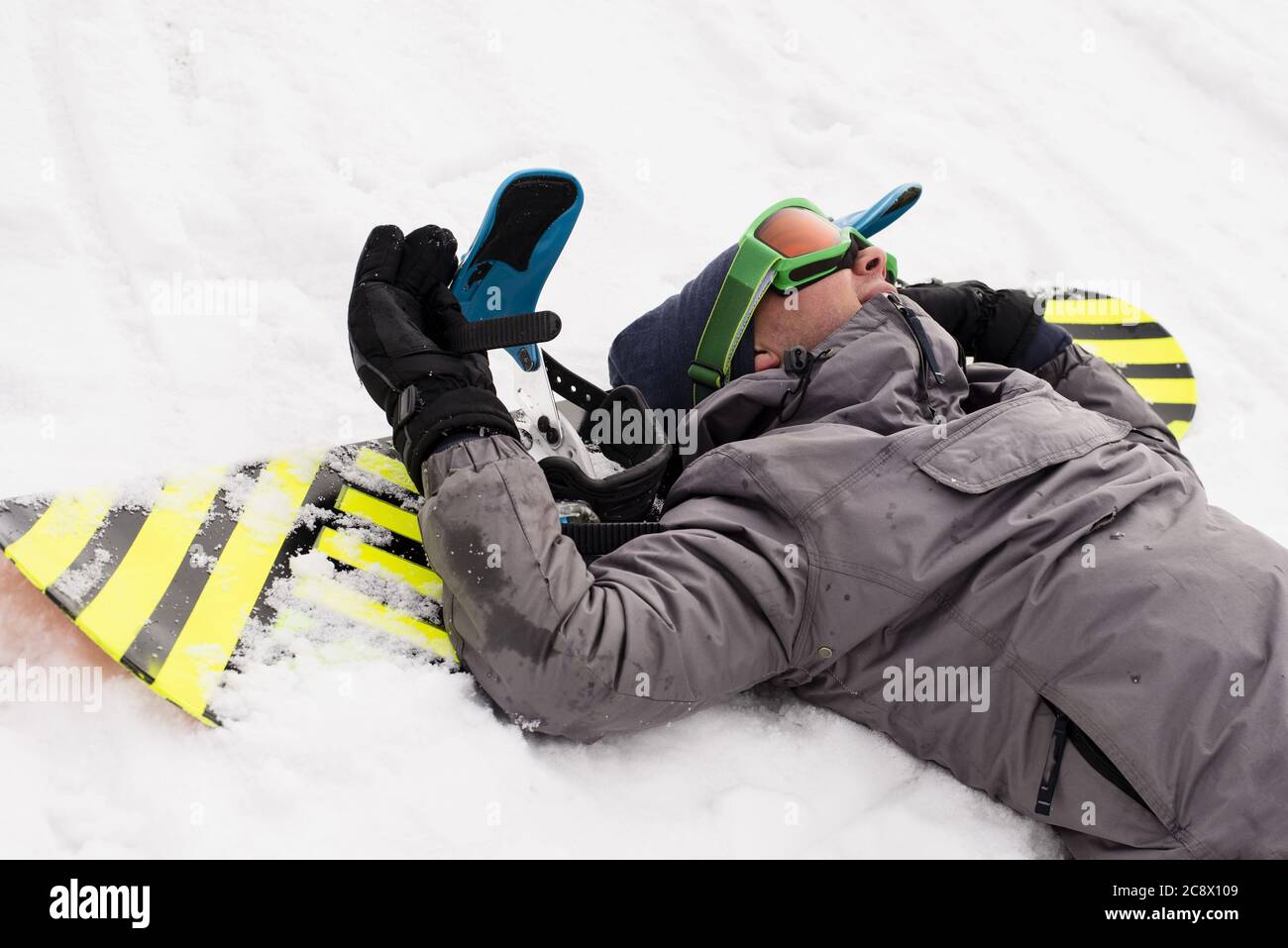 Caucasian male lying on the snowy ground after falling down from ...