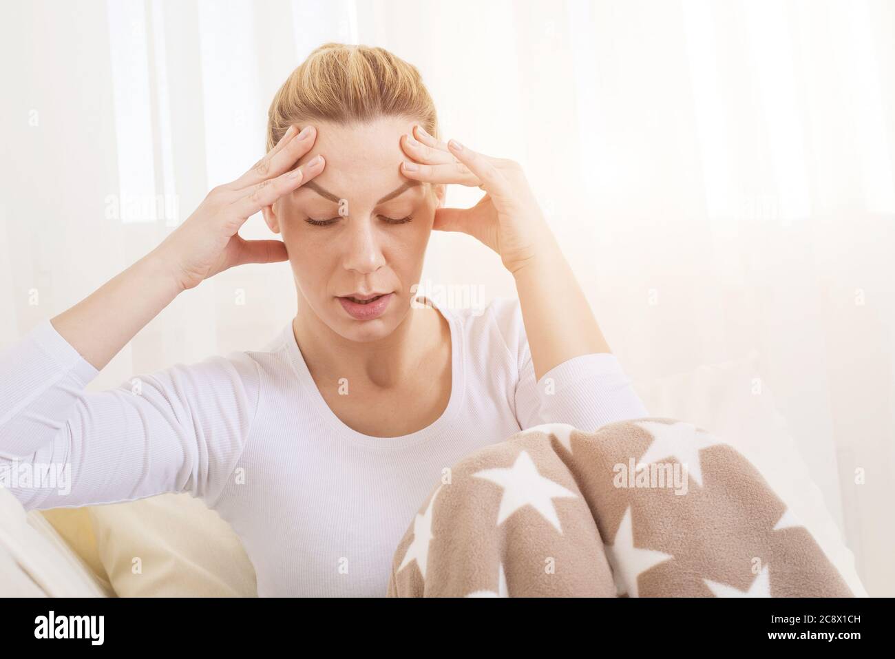 Caucasian woman sitting on a couch looking very worried and frustrated ...