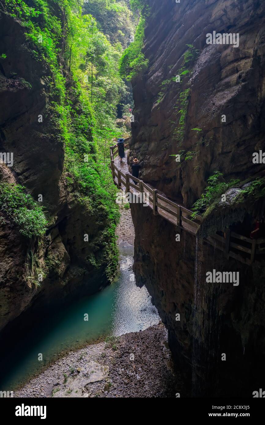 Tourists walking on a wooden artificial cliff attached walkway path ...