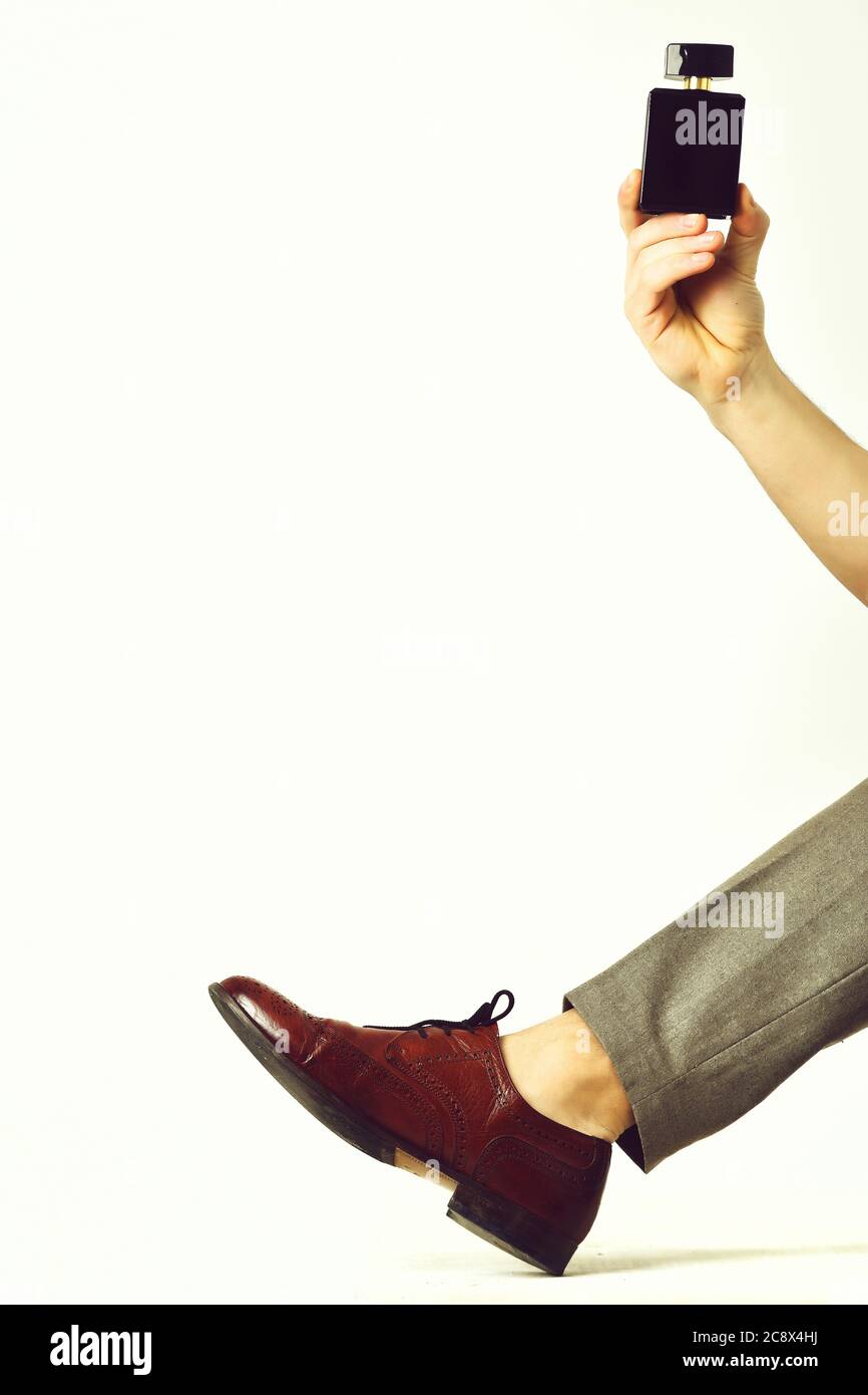 Male leg with brown fashion shoe and strong hand holding bottle of ...