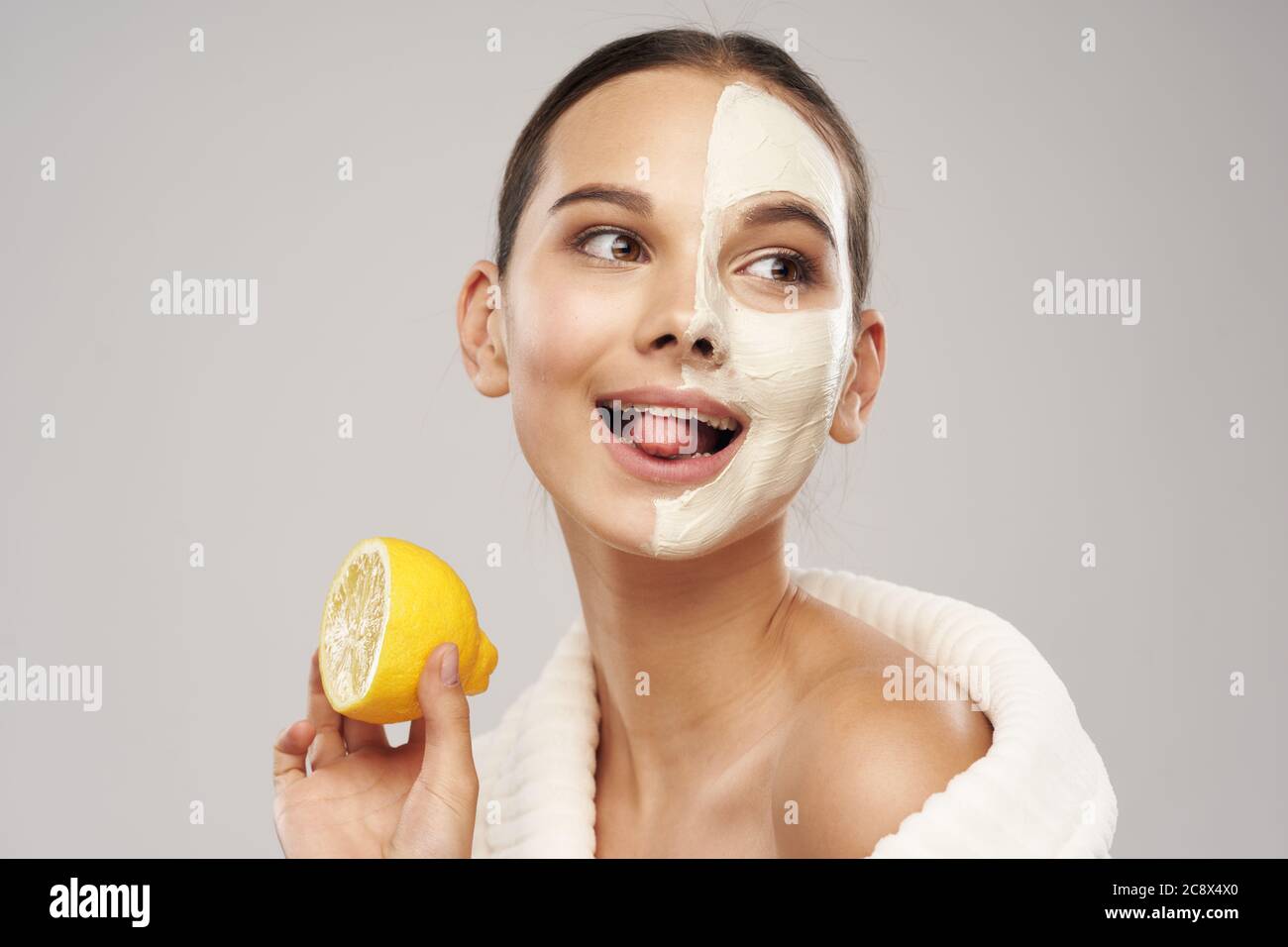 Clean skin white mask on the face and a slice of lemon in the hand girl ...
