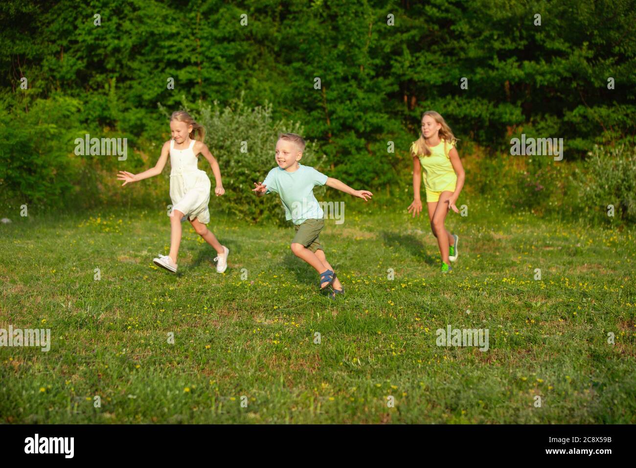 Kids, children running on meadow in summer's sunlight. Look happy ...
