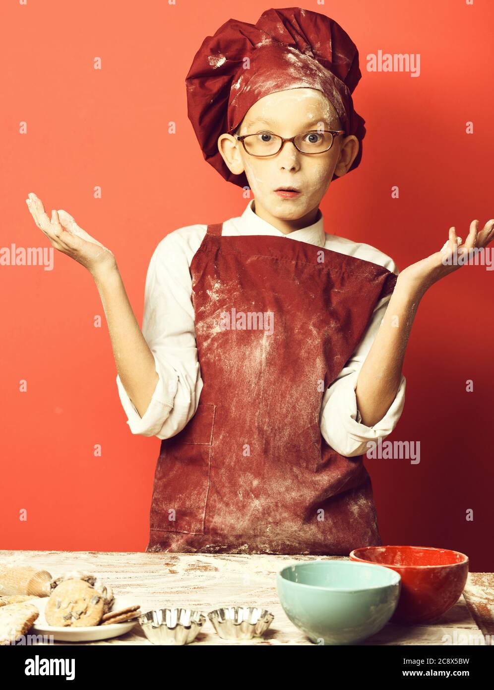 young boy cute cook chef in uniform and hat on stained surprised face ...