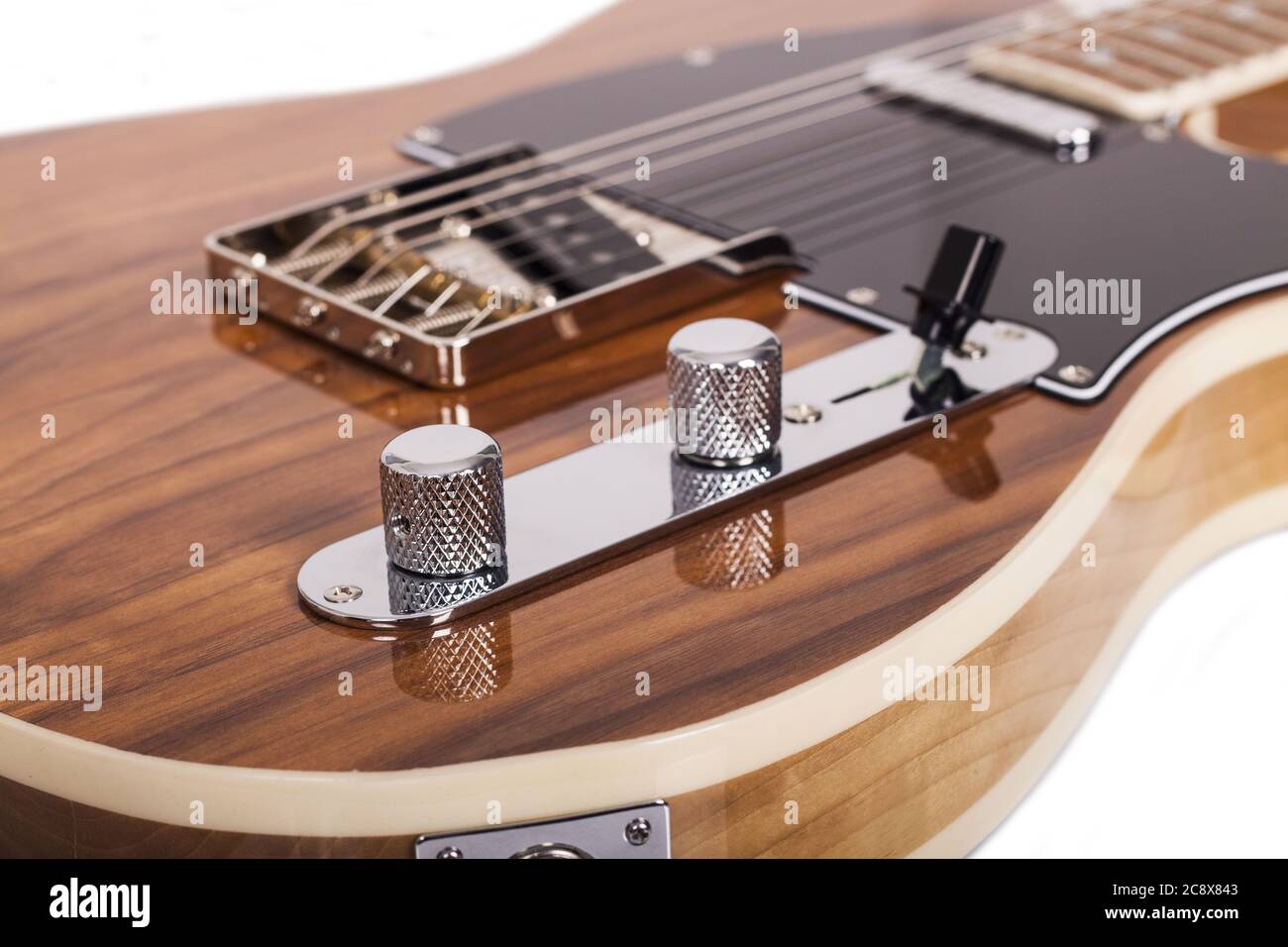 Closeup of a brown electric guitar with a wood tone on a white surface ...