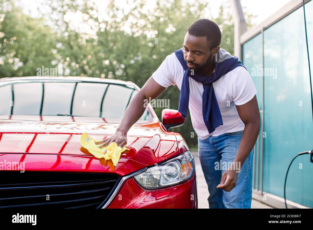 Horizontal shot of a young African American man cleaning the hood on ...
