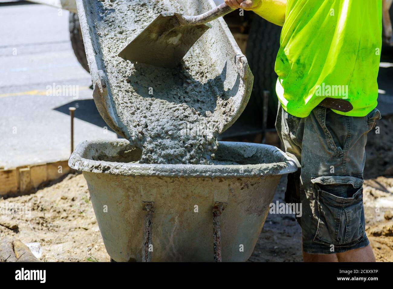 Wheelbarrow with shovel full of cement concrete of concrete mixer truck ...