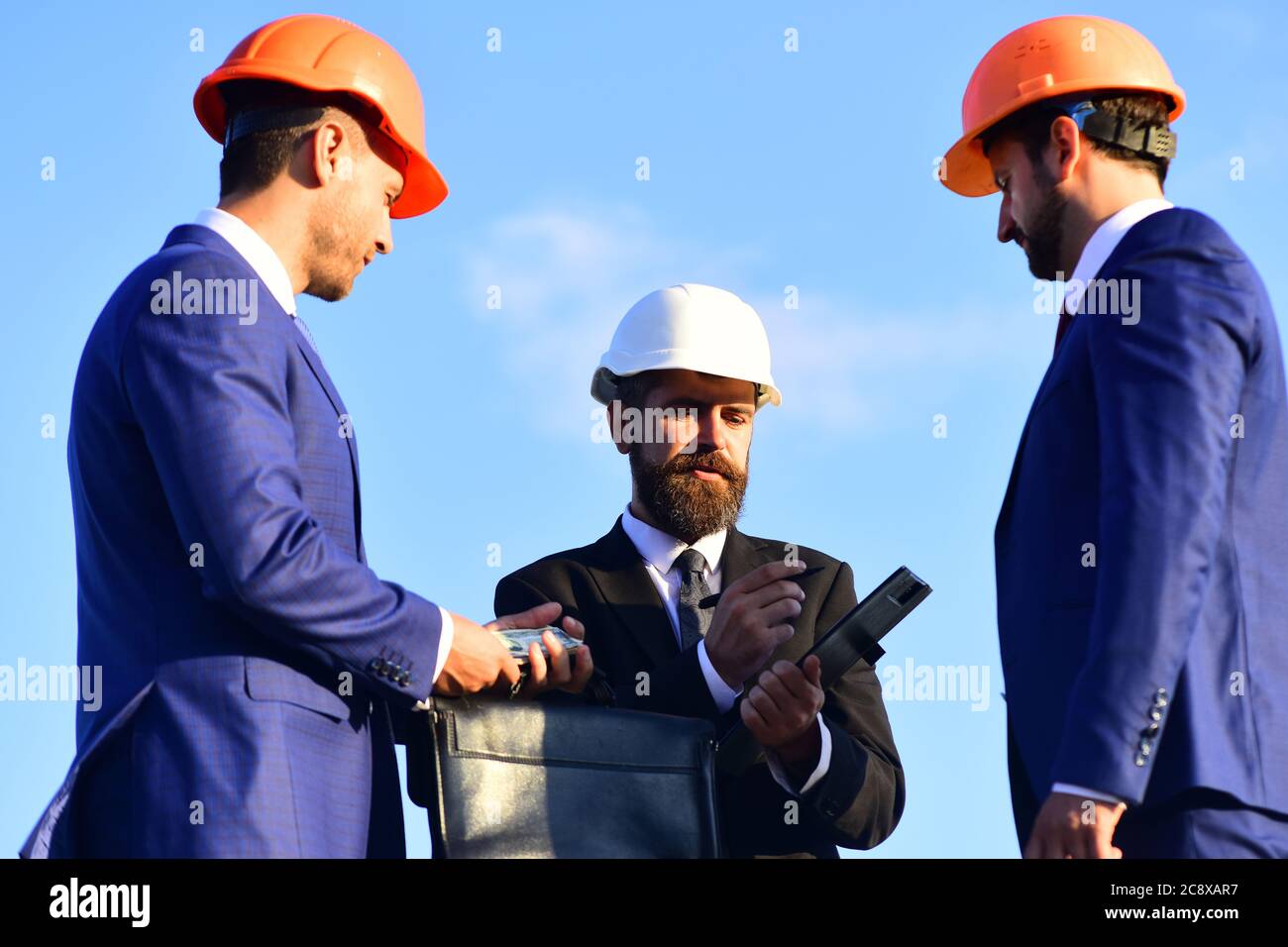 Workers and engineer hold meeting on sky background. Construction and ...