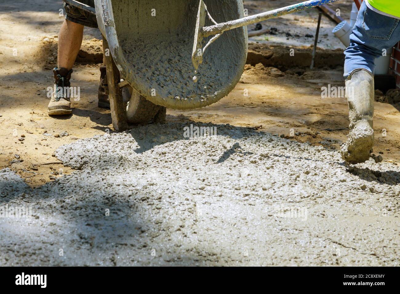 Labour builders at construction site filling formwork with cement ...