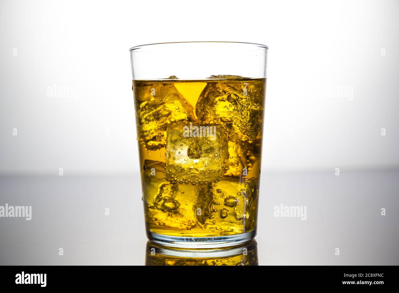 a glass of yellow drink with ice cubes Stock Photo - Alamy