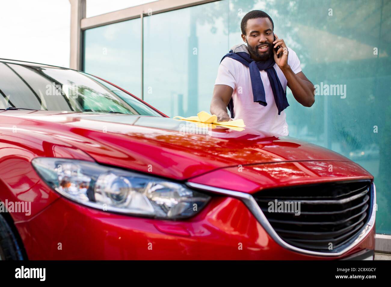 Car celaning and polishing outdoors. Portrait of young African man ...