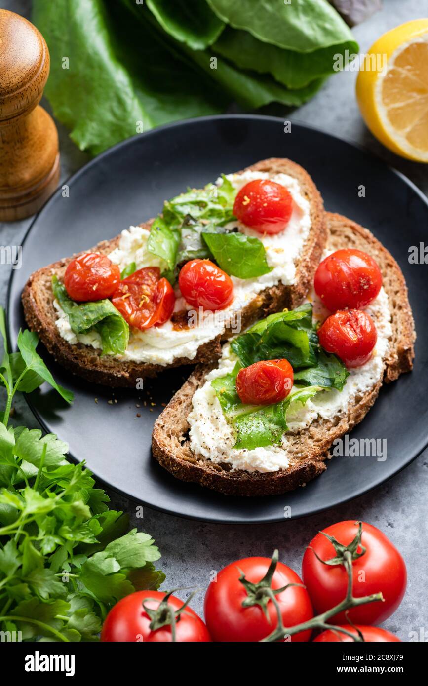 Bruschetta with ricotta and tomatoes on black plate. Gourmet italian ...