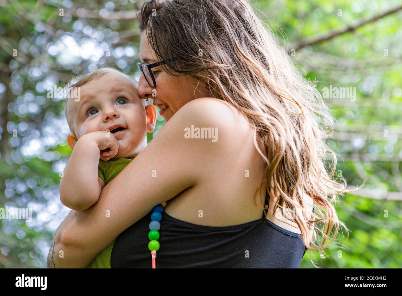 Portrait of a mother and her baby, outdoor in the woods. Mommy is holding her son in her arms ...