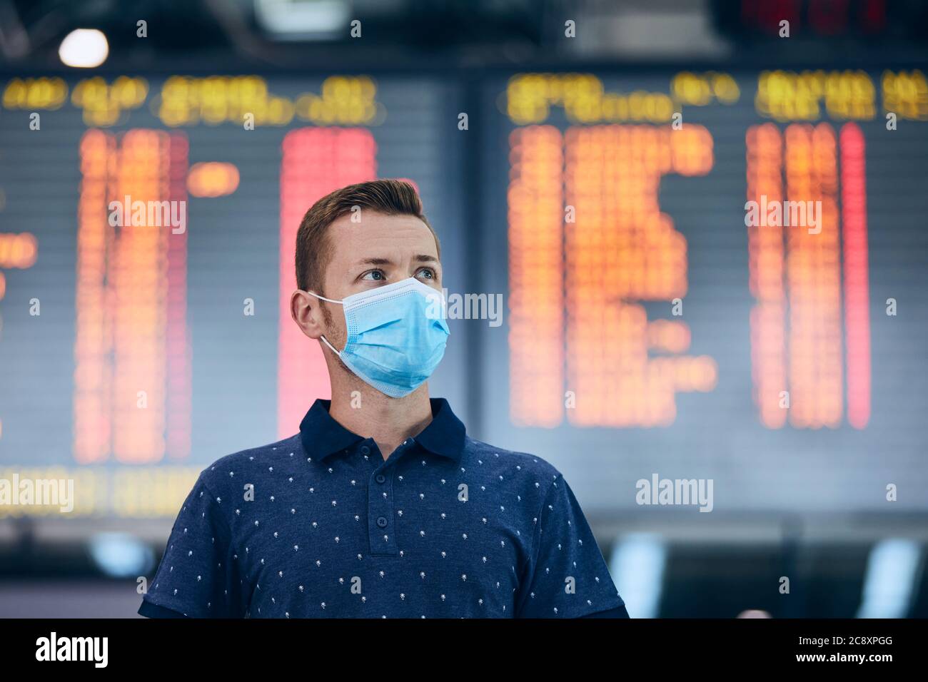 Man wearing face mask against airport departure board. Themes new ...