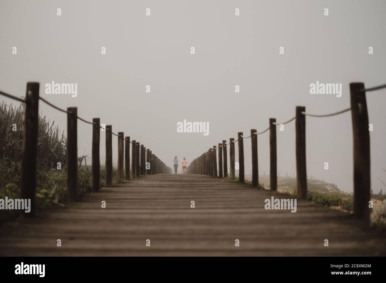 Wooden bridge with two people running in the distance Stock Photo - Alamy
