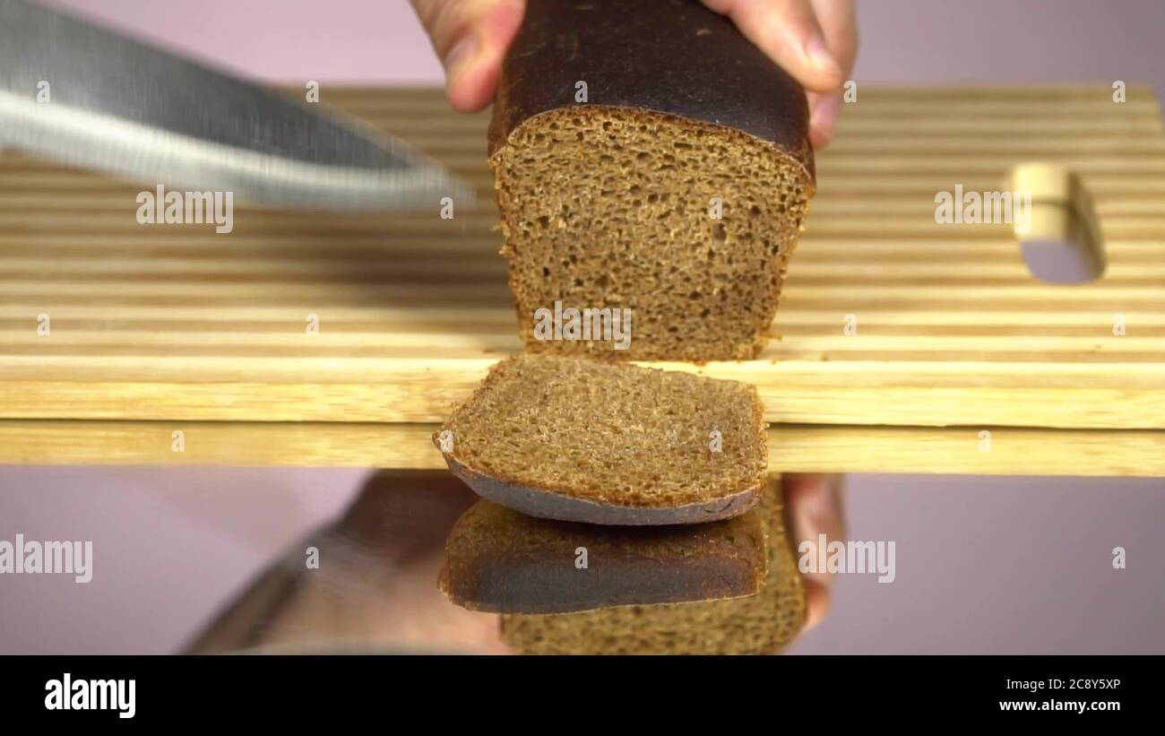 front view of brick of bread. Mans hand take off a front part of bread ...