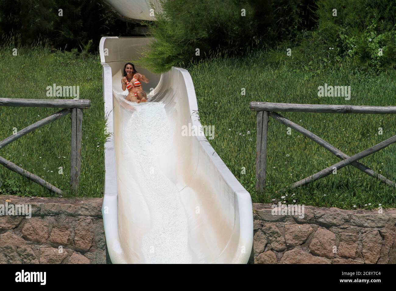 Girl in bikini having fun when falling down water slide in water park ...