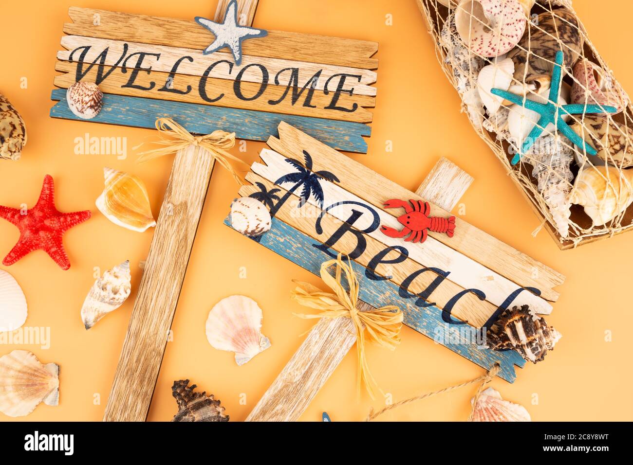Wooden signs welcome beach, starfish and shells on yellow background ...