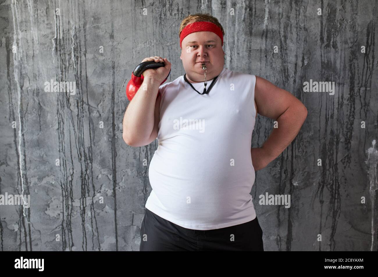 strong fat male pumps muscles with a kettlebell, overweight man show ...