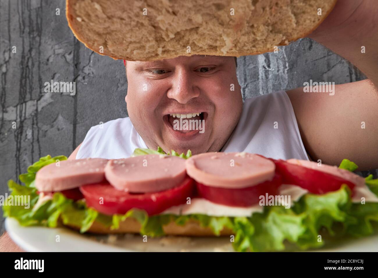 happy fat caucasian man is opening sandwich top, young man loves ...