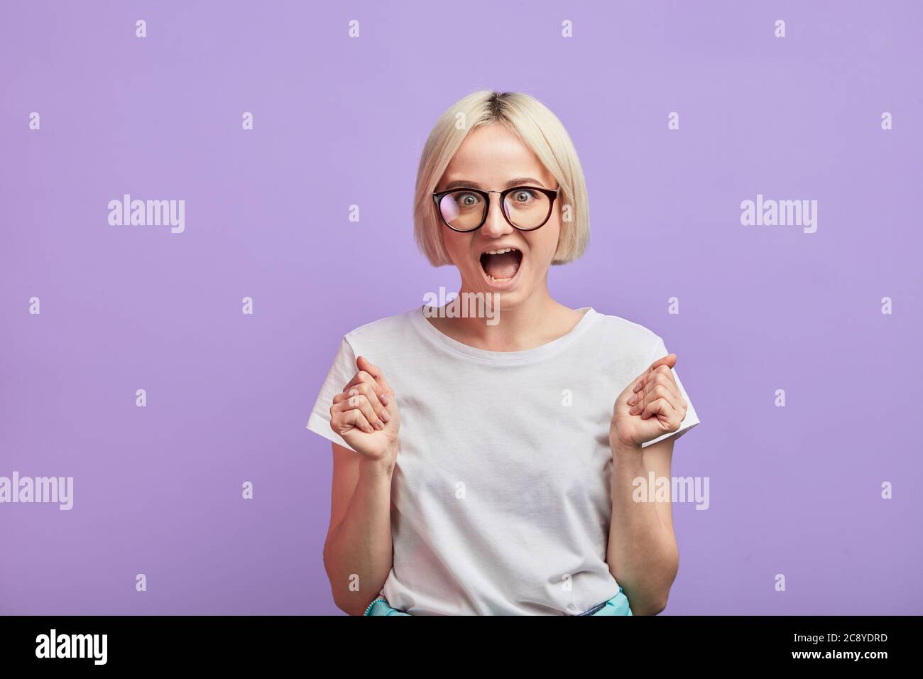 Shocked surprised woman clenches fists with happiness, opens mouth ...