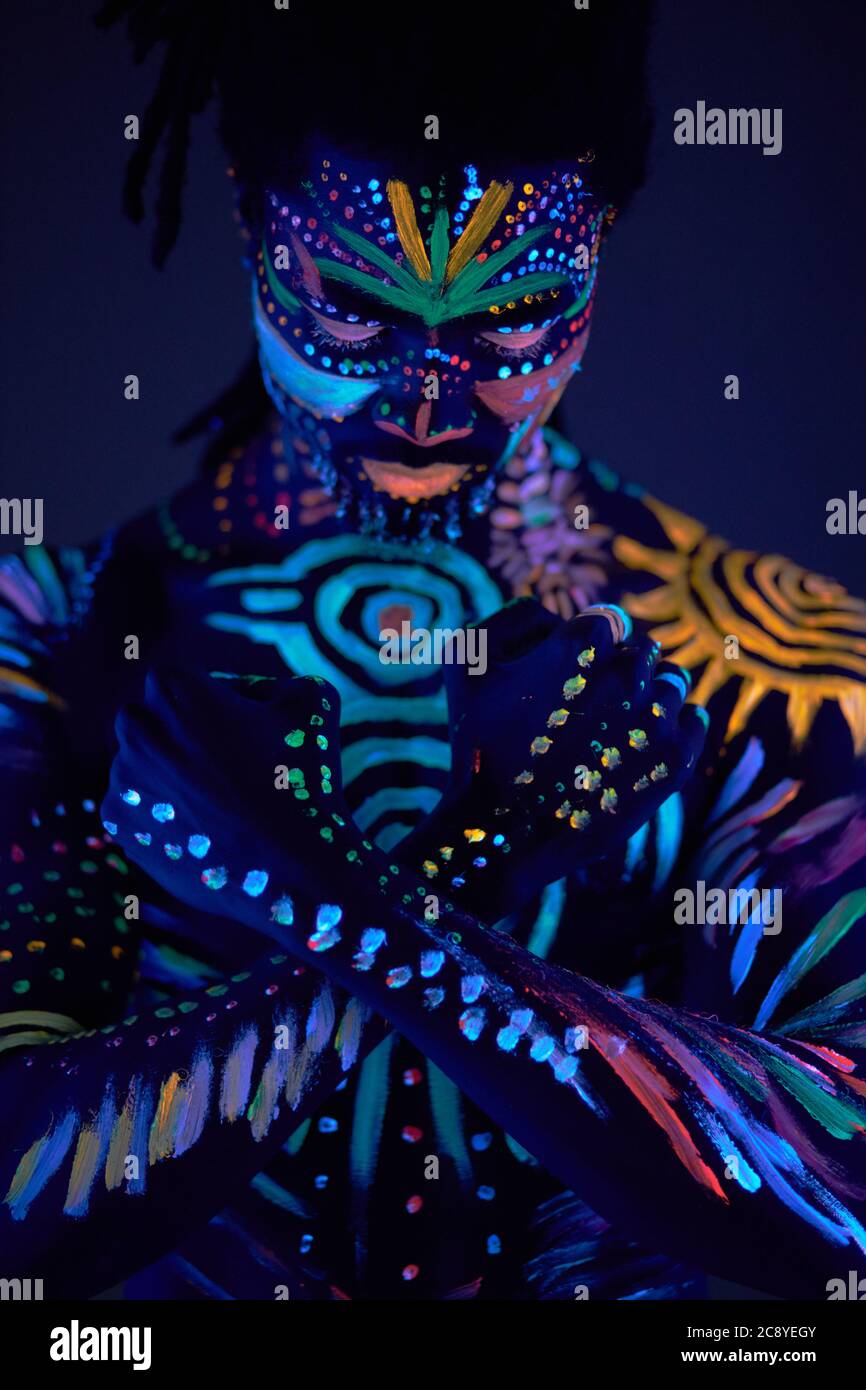 portrait of strong muscular male covered with fluorescent luminescence ...