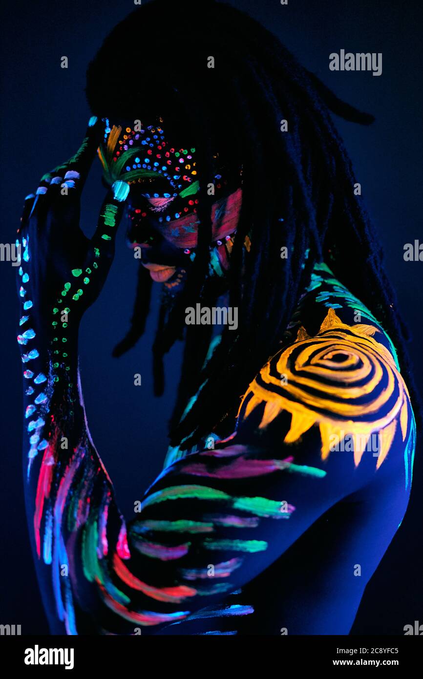 mysterious african male with fluorescent body art glowing in dark space ...