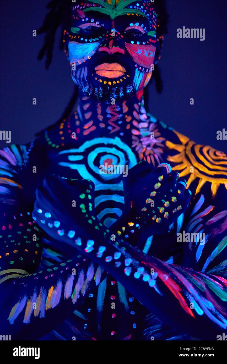 young handsome african man with fluorescent prints on body glowing on ...